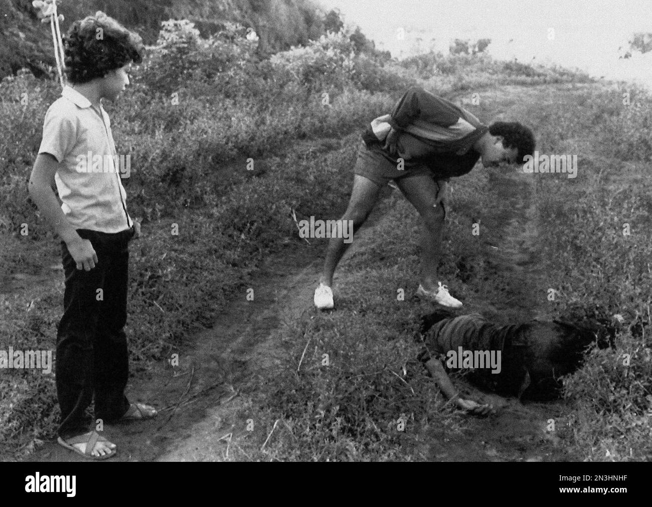 Two boys inspect the body of a dead female guerrilla, killed in ...