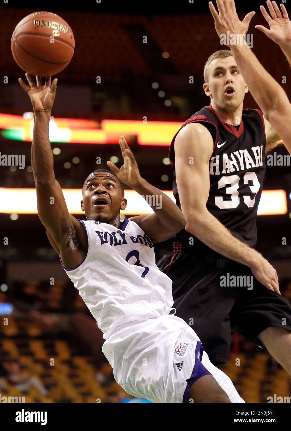 Holy Cross guard Justin Burrell, left, shoots at the basket as Harvard ...