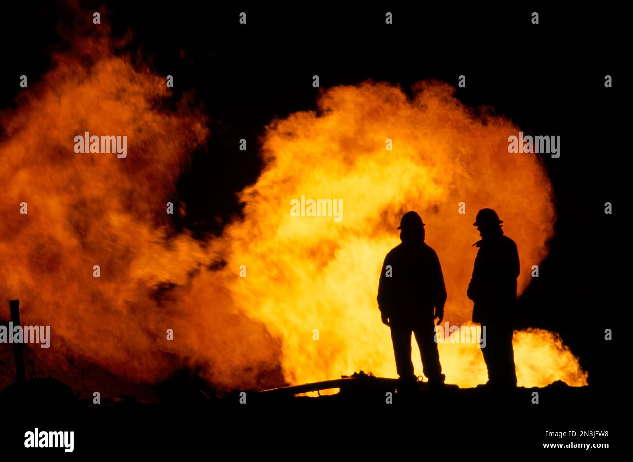 Oil field workers watch a flare at a natural gas drilling site ...