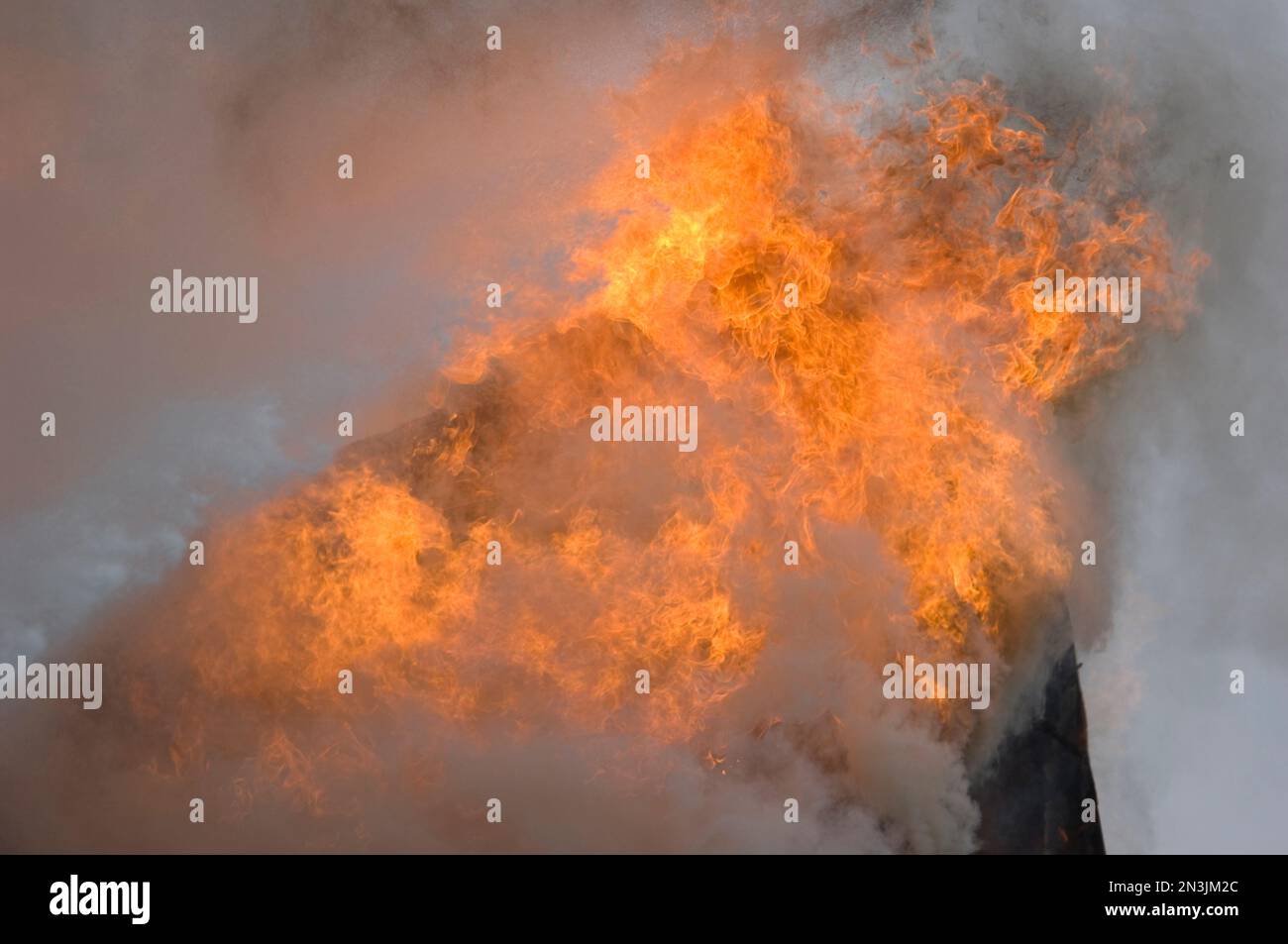 Bright burning flames and smoke in a house fire. Local fire fighters ...