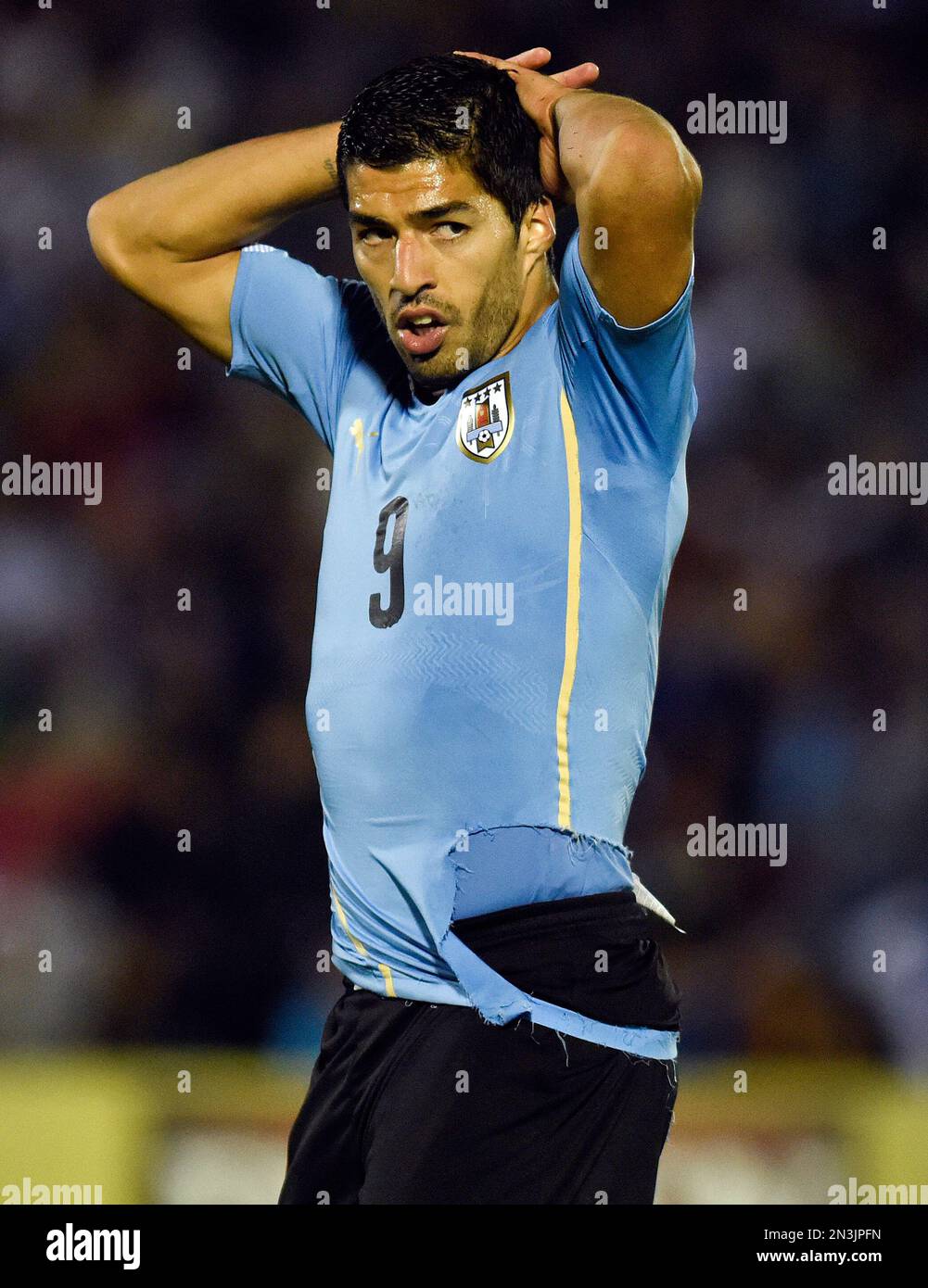 Uruguay's Luis Suarez, stands with his ripped jersey after missing a ...