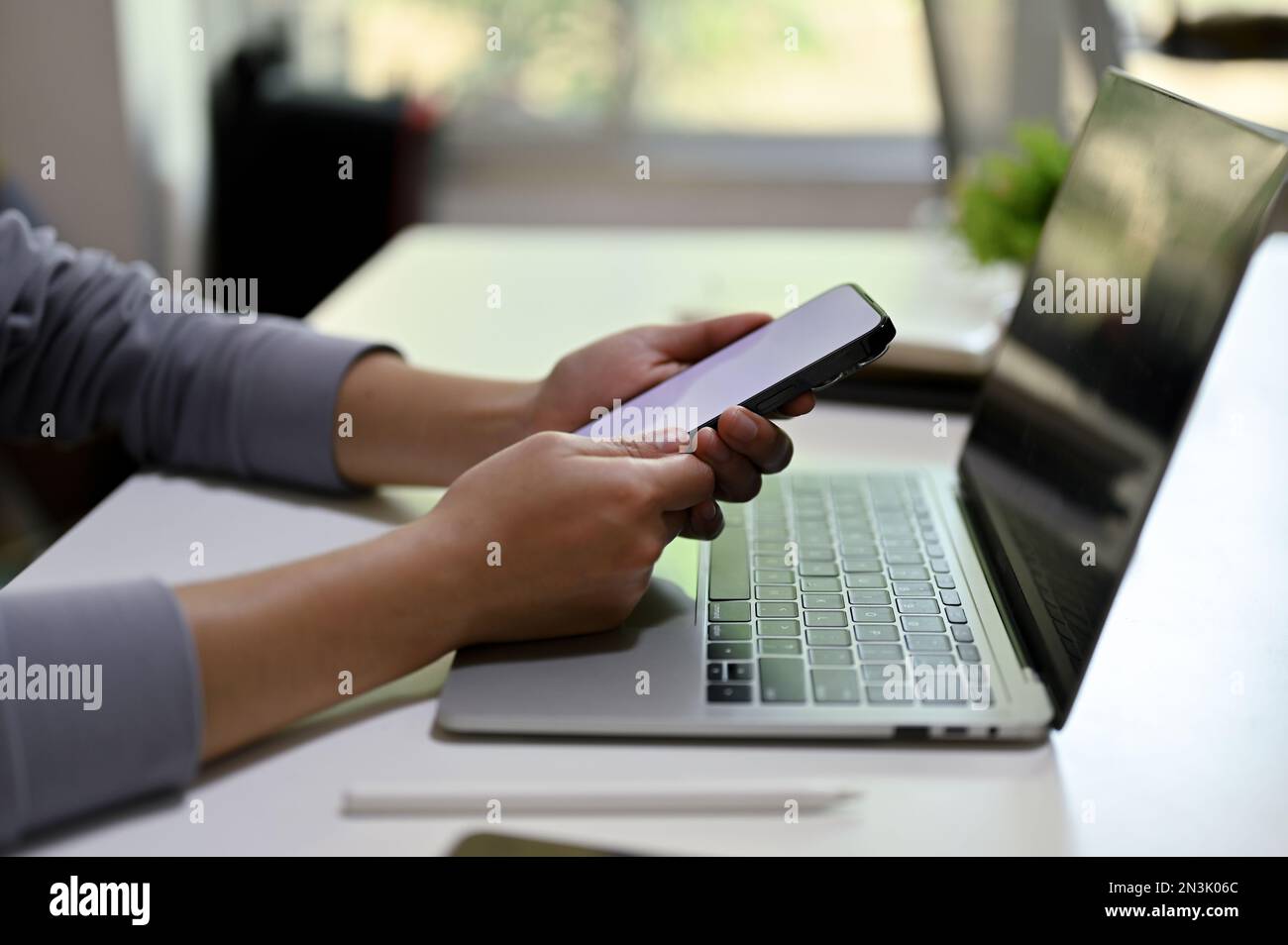 Side view of a businesswoman using her smartphone at her office desk ...
