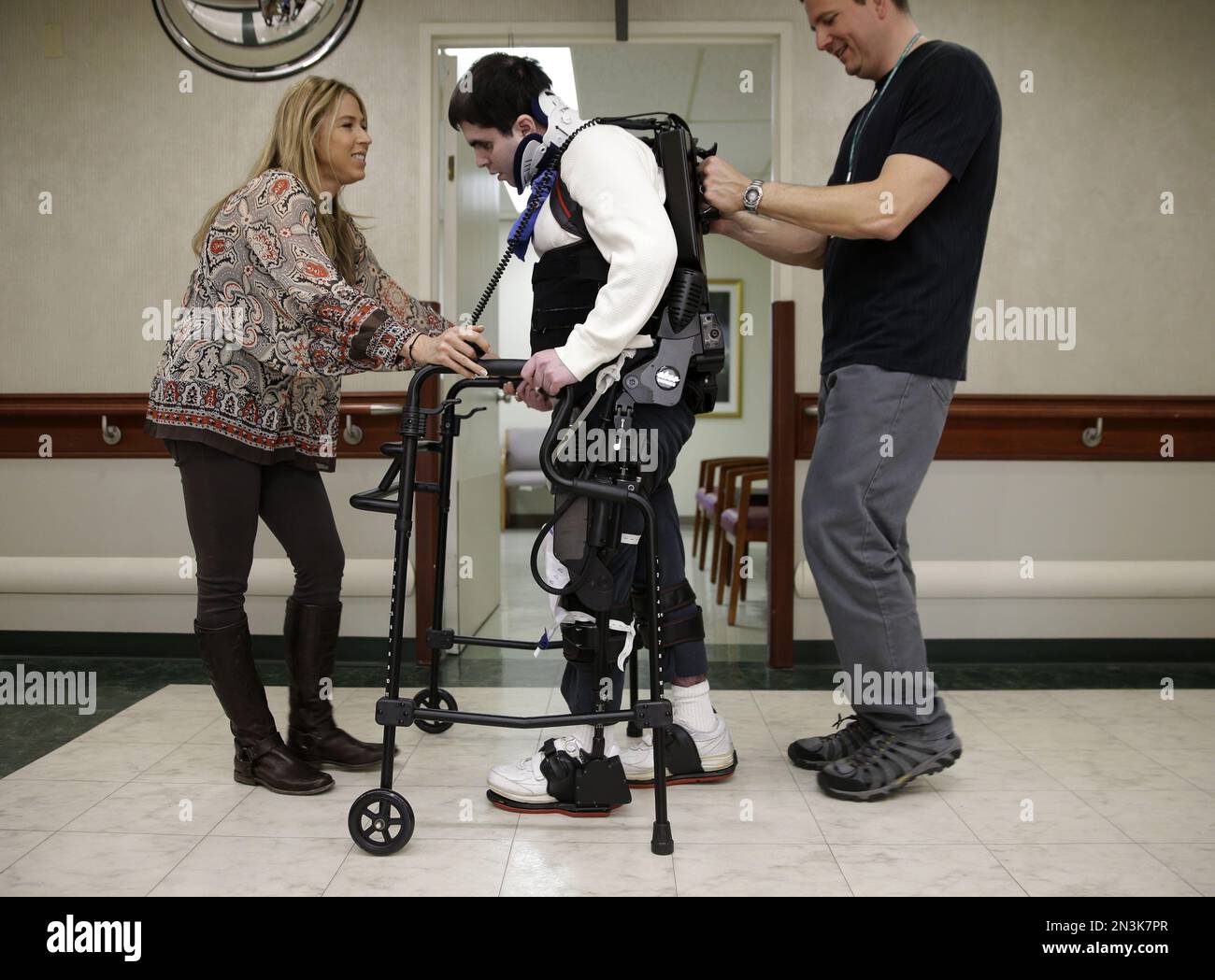 James Cody, 29, center, walks with the aid of a bionic exoskeleton and ...