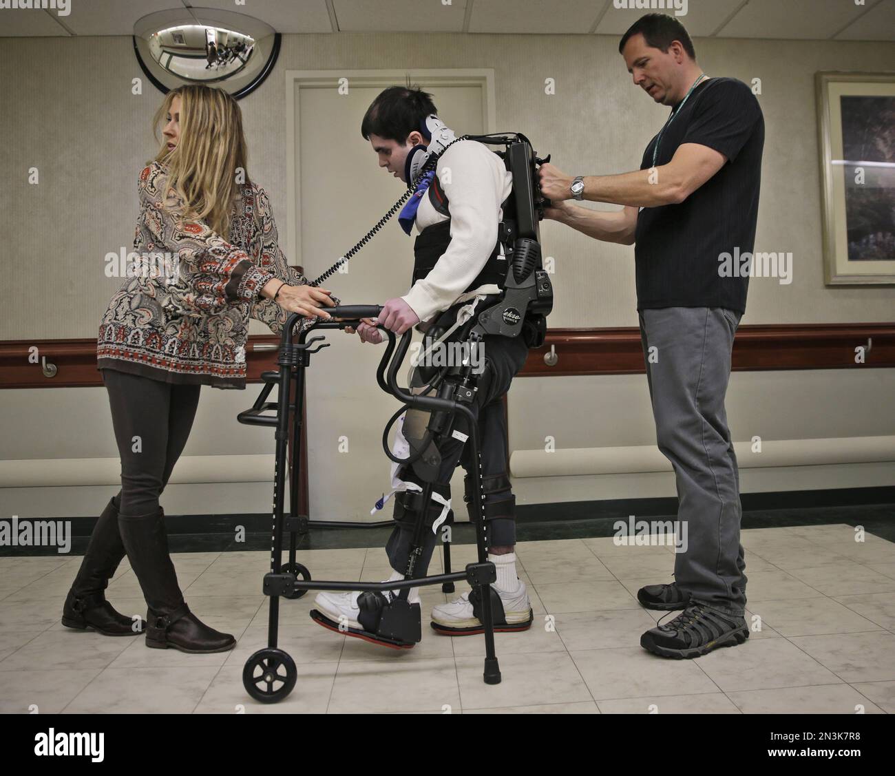James Cody, 29, center, walks with the aid of a bionic exoskeleton and ...