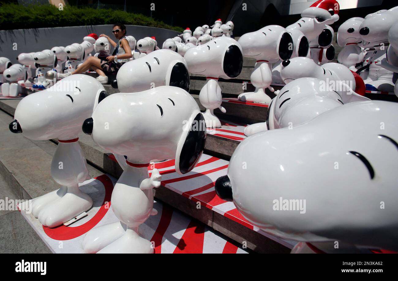 A Thai woman poses with snoopy models which decorate in front of a ...
