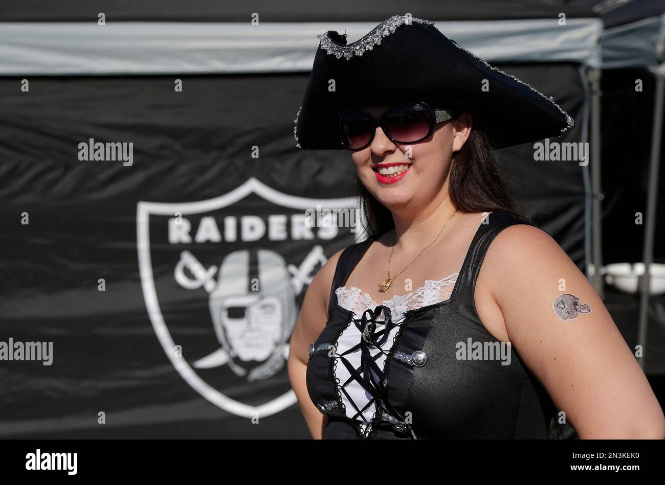 An Oakland Raiders fan poses for photos while tailgating in the O.co ...
