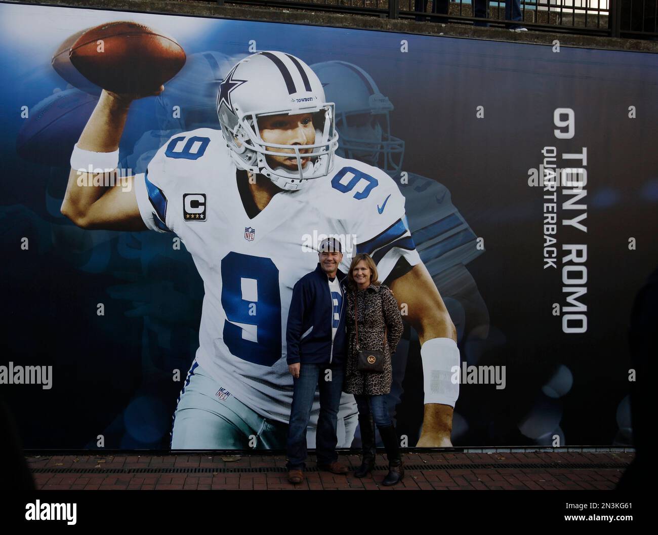 Spectators poses next to a poster of Dallas Cowboys quarterback Tony ...