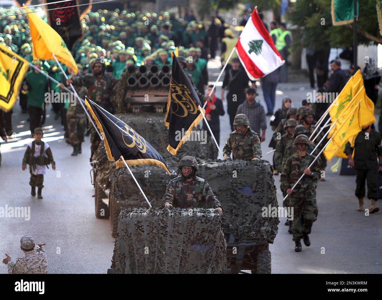 Hezbollah fighters stand on their armed vehicles and hold their party ...