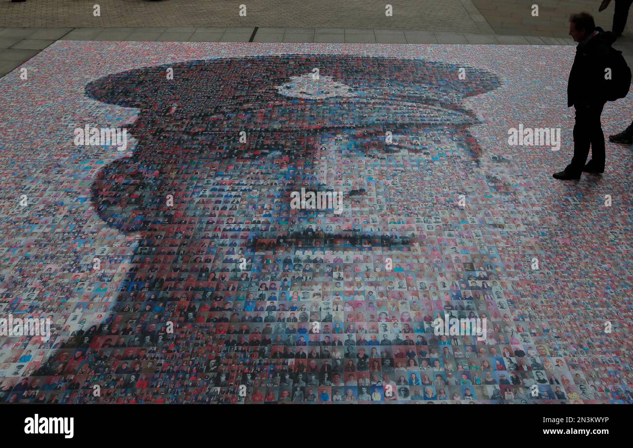 A man walks on a digital mosaic of photographs of people, depicting ...
