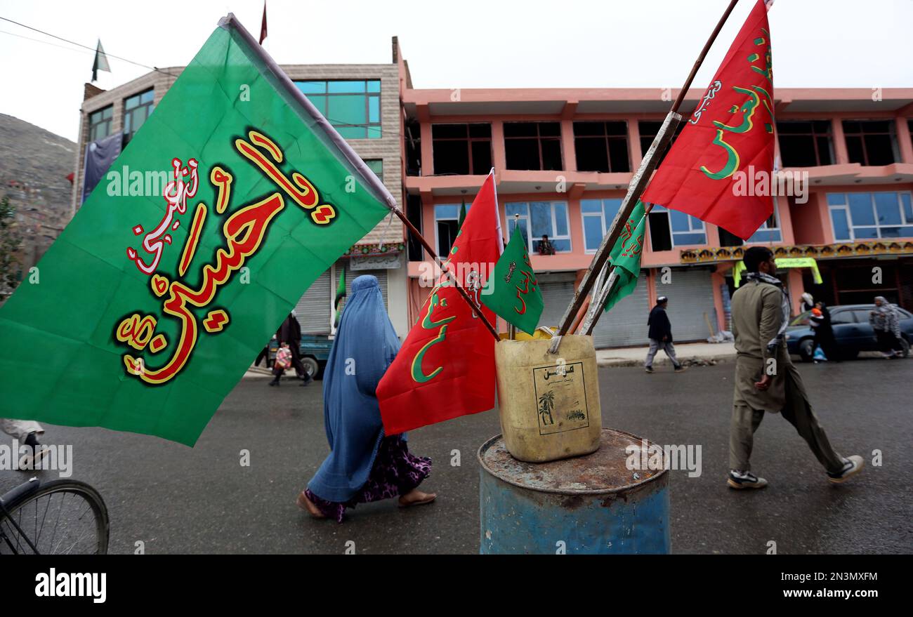 An Afghan woman walks past religious flags, ahead of the Ashoura ...
