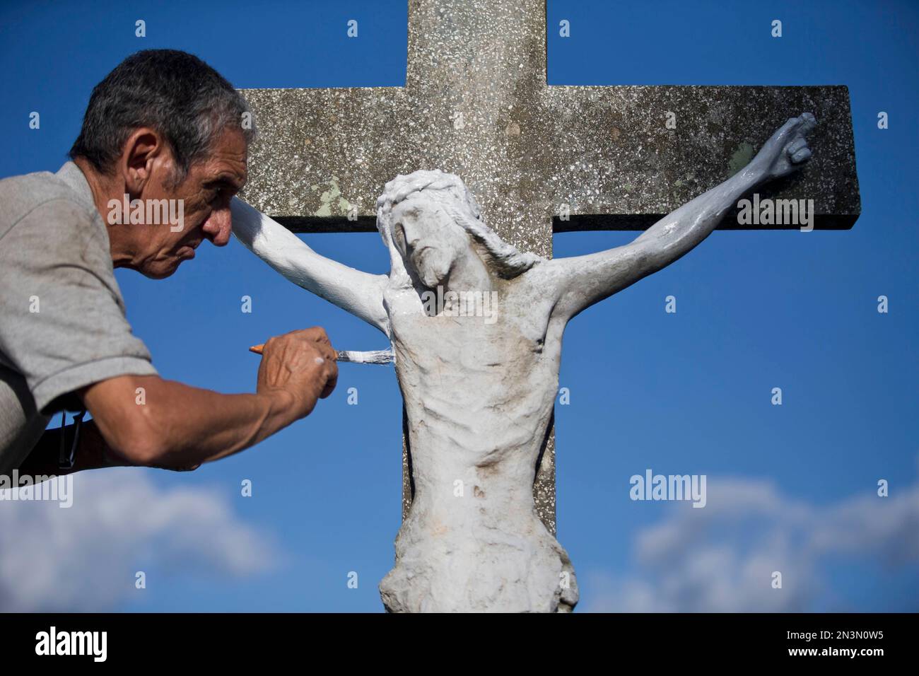 Santiago Gonzales fixes up the statue of Christ on his grandmother's grave during Day of the ...
