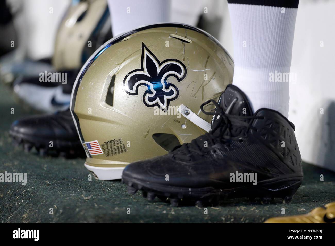 A New Orleans Saints helmet sits ready at the feet of a player on the ...