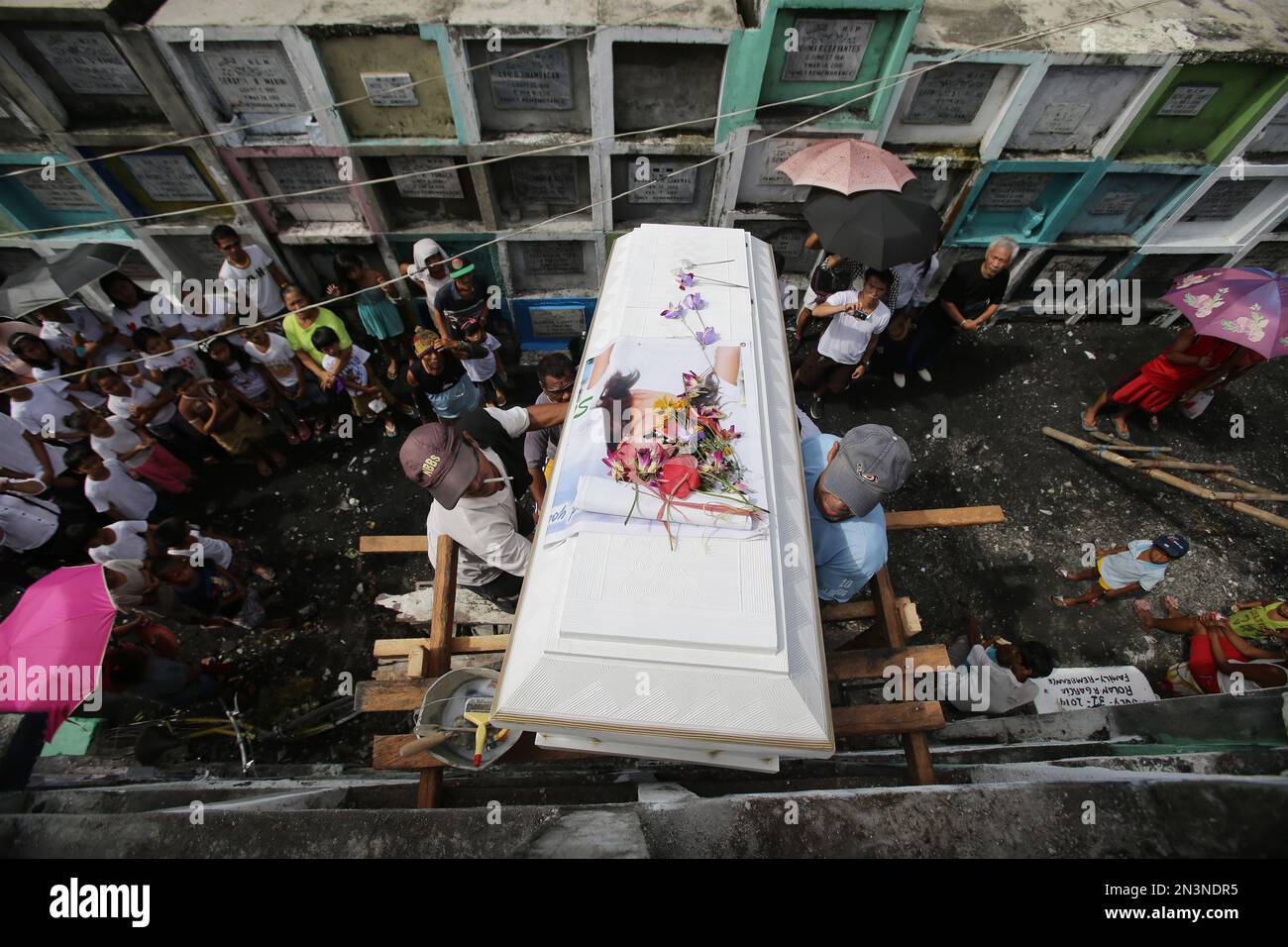 Workers carry a coffin on top of multi-layered tombs during a funeral ...