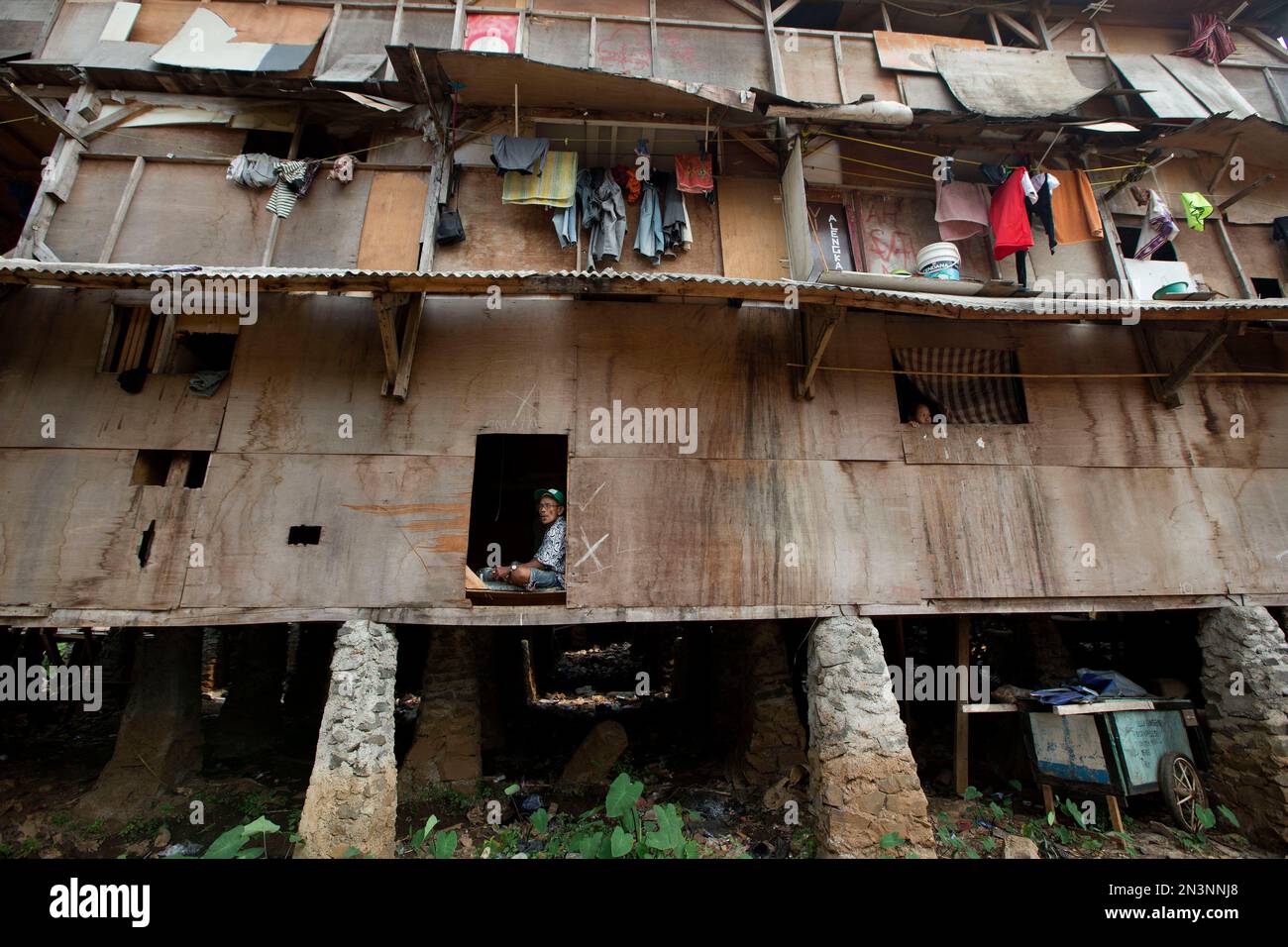 A man sits by the window in his house in a South Jakarta slum in ...