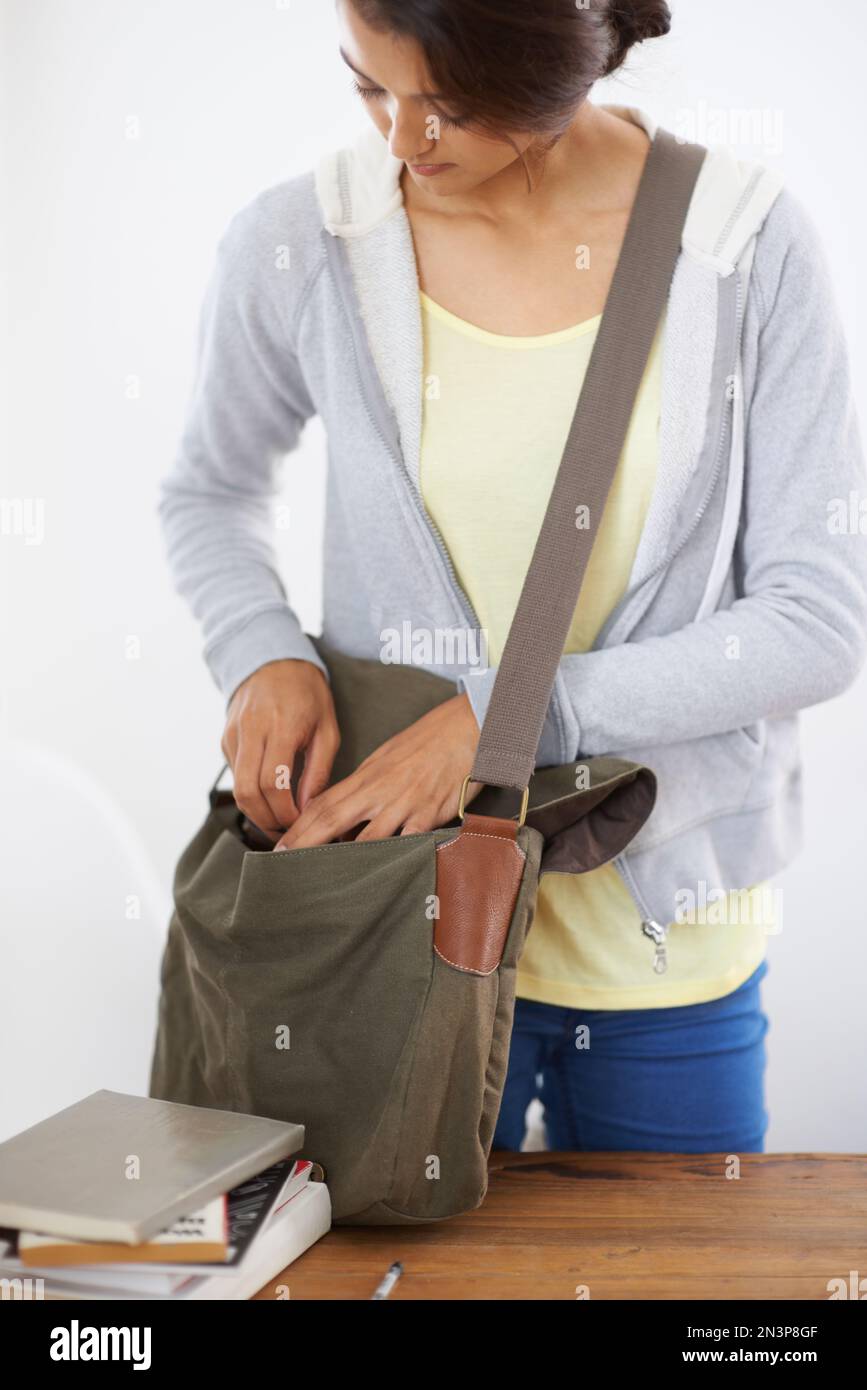 Preparing for a day at college. young student packing books into her ...