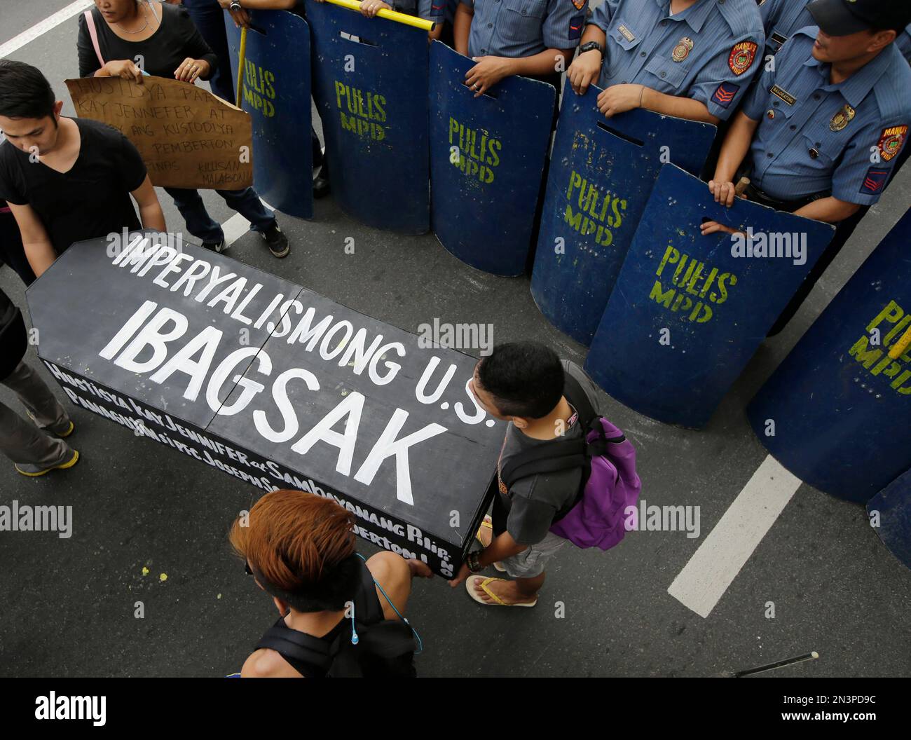 Riot police watch protesters placing a mock coffin during a rally ...