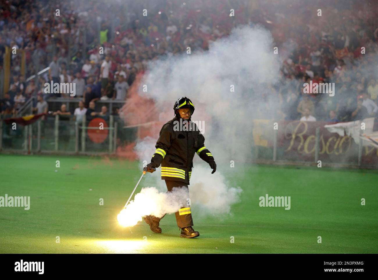 Firefighter carries a flare off the pitch during the Group E Champions ...