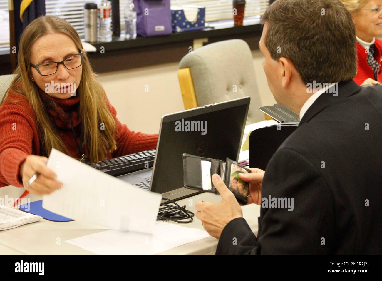 Election poll worker Carley Dunn, left, assists U.S. Sen. Mark Begich ...