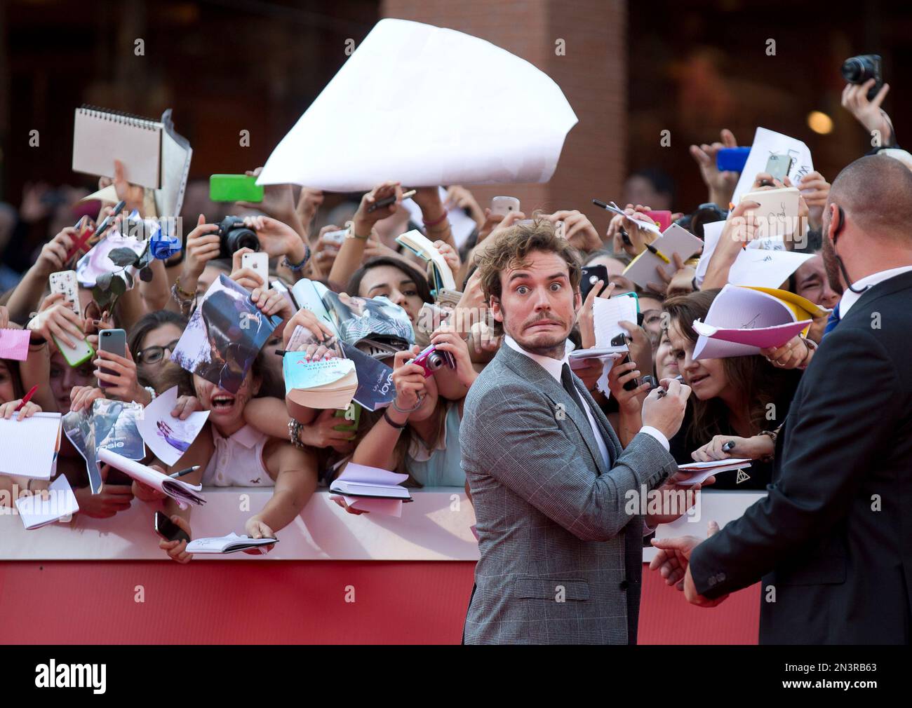 Actor Sam Claflin signs autographs as he arrives on the red carpet for ...