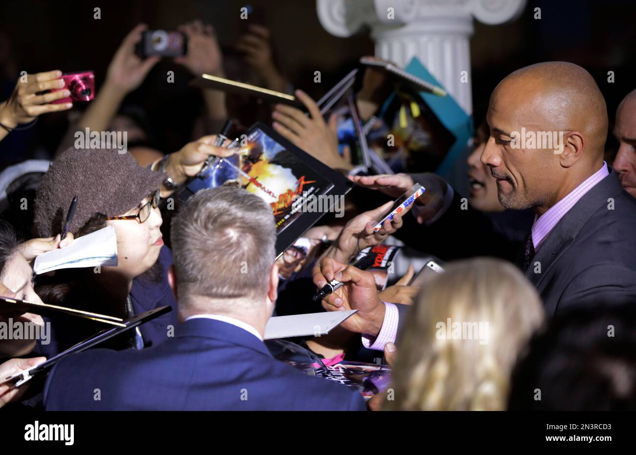 American actor Dwayne Johnson gives his autograph to his fans as he ...