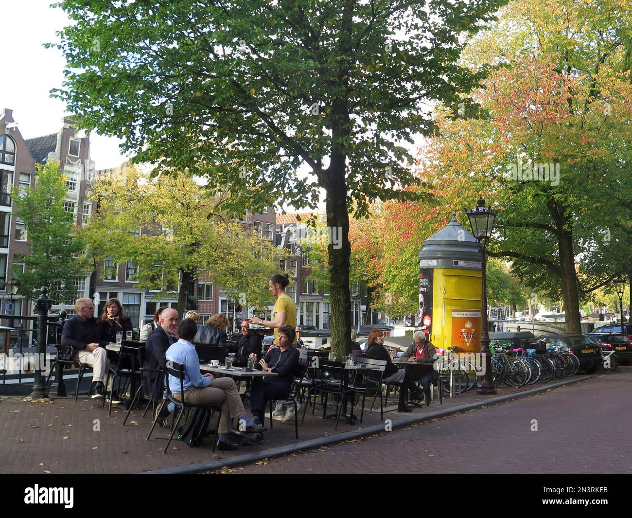 A waiter serves drinks to people sitting on a terrace in front of a ...