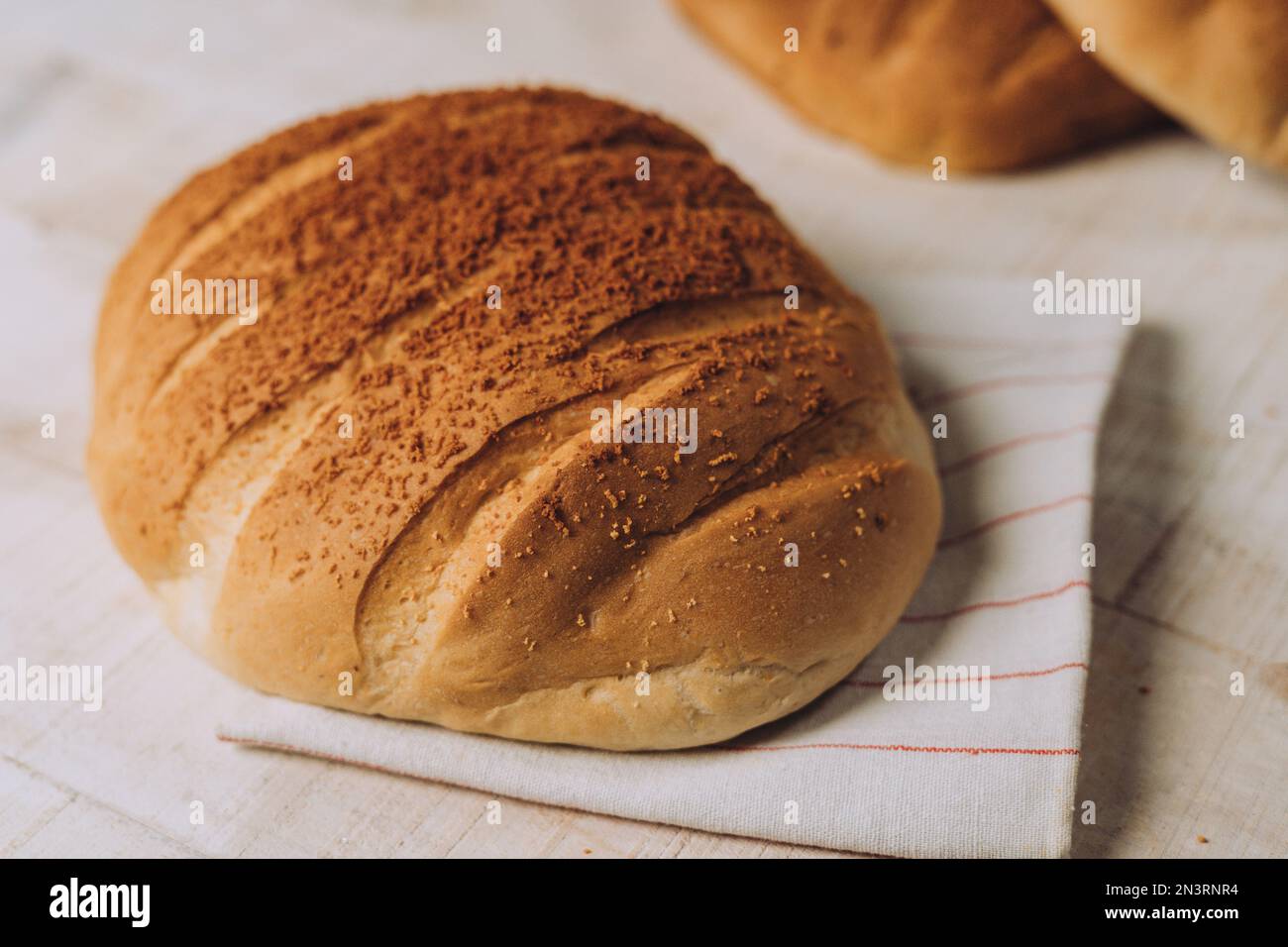 A closeup of freshly baked crusty bread put on the white table surface ...