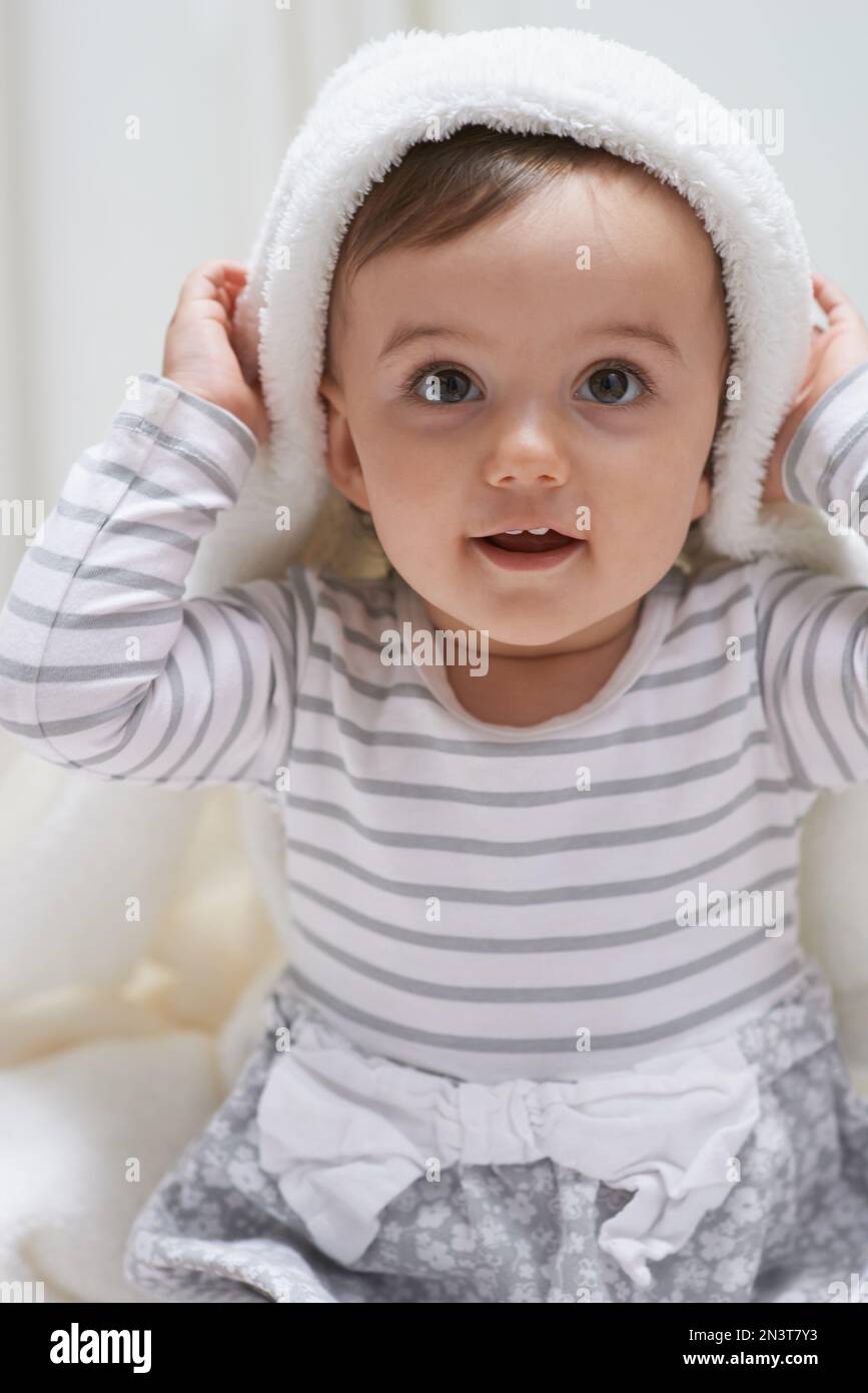 Peek-a-boo. a cute little baby girl sitting on the floor playing with ...
