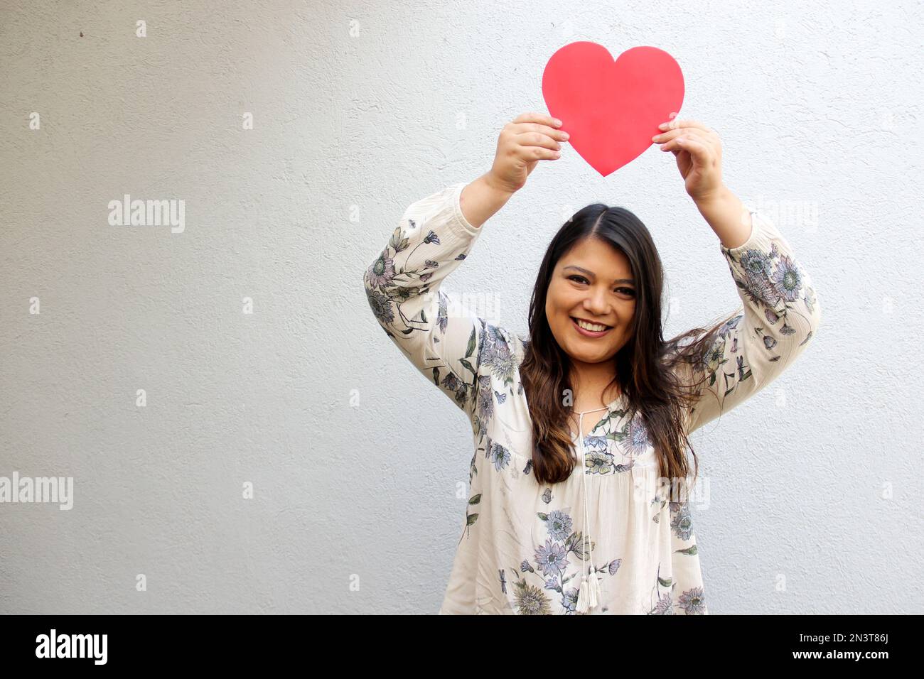 Latin adult woman shows big red heart with enthusiasm for the arrival ...