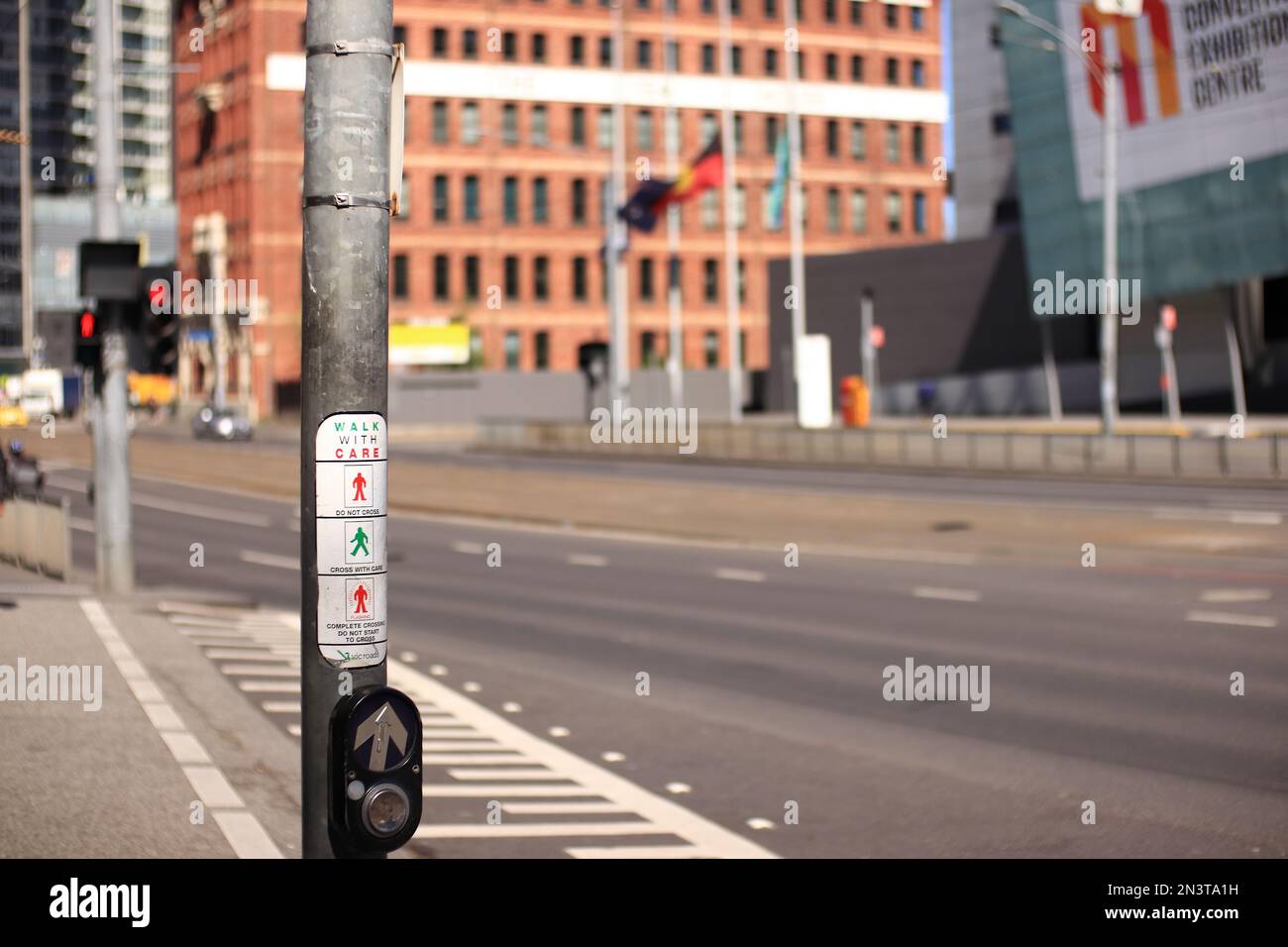 A selective focus of a metallic pillar with "walk with care" sign near ...