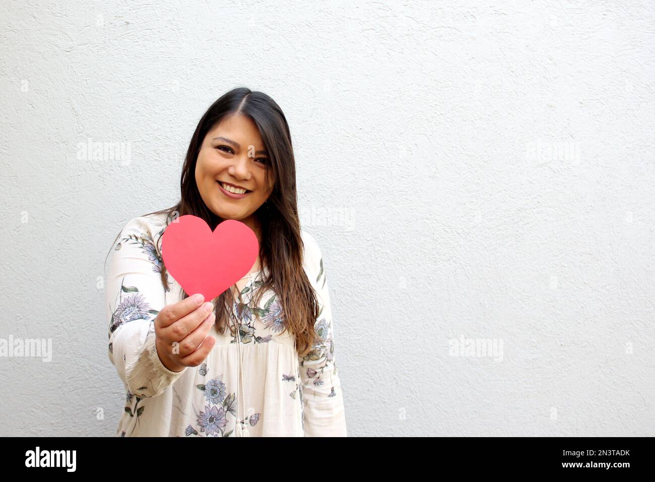 Latin adult woman shows big red heart with enthusiasm for the arrival ...