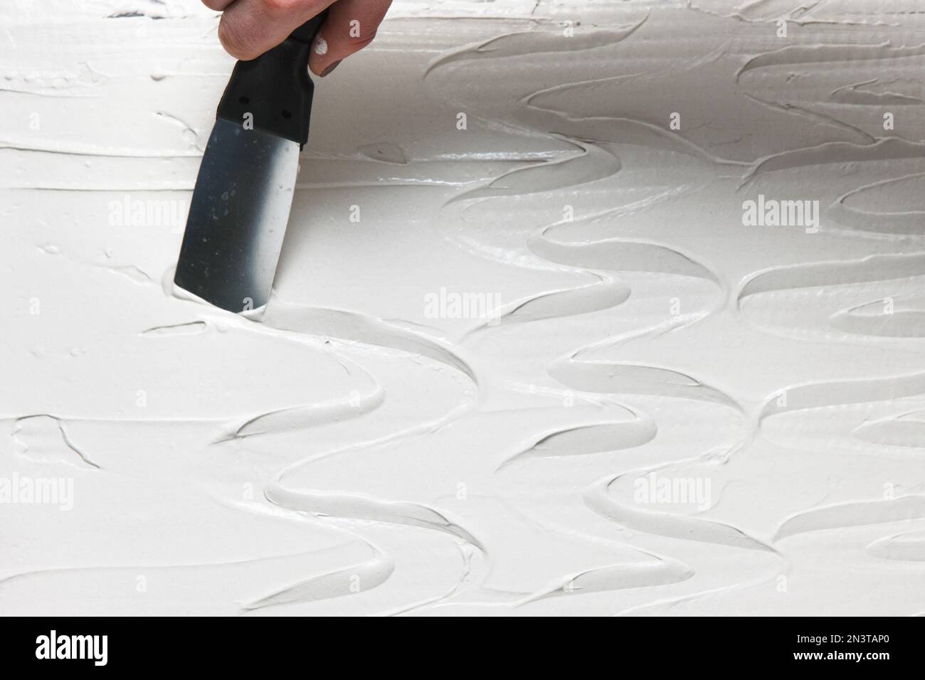 Hand with spatula make texture on white plaster Stock Photo - Alamy