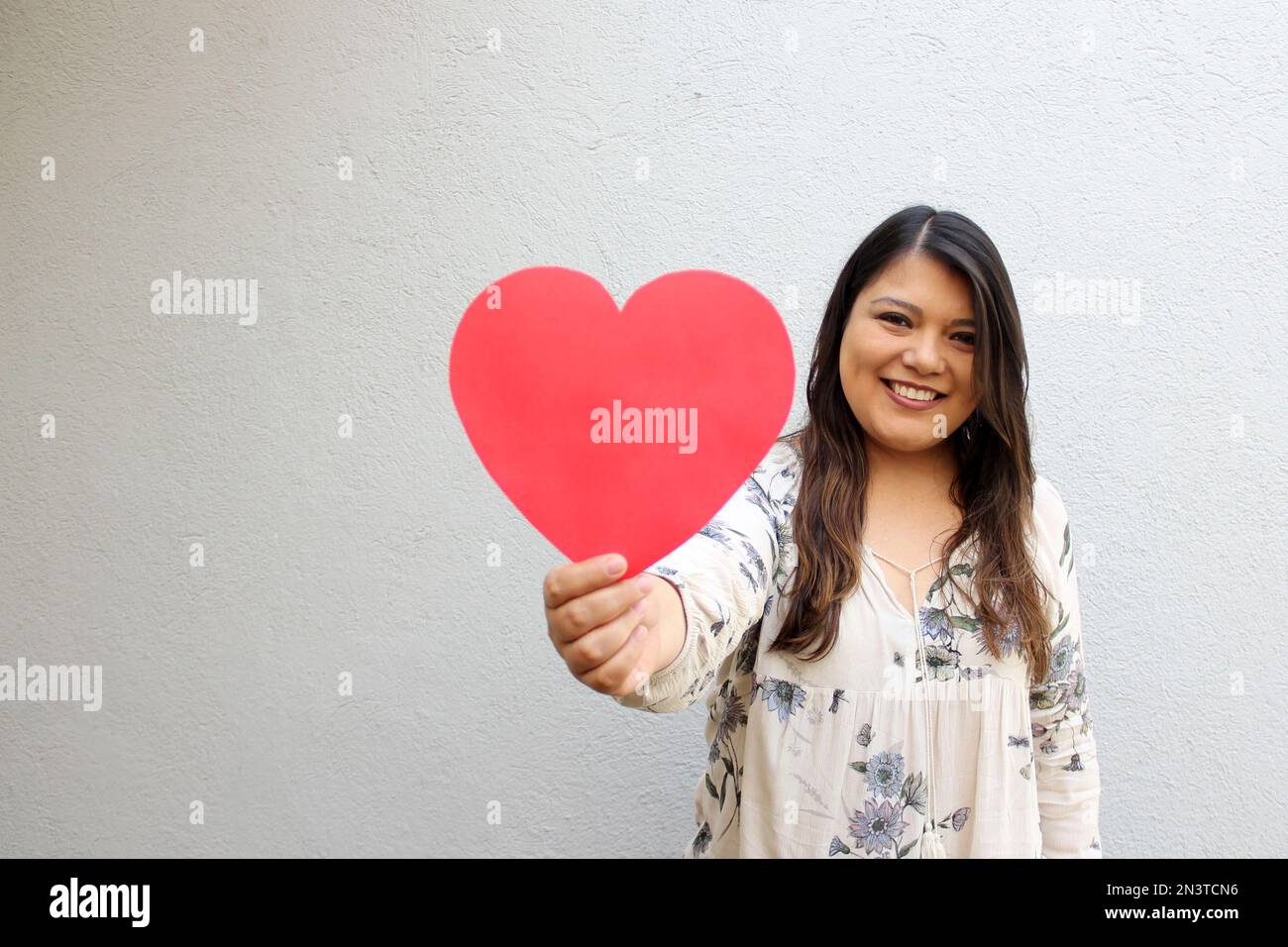Latin adult woman shows big red heart with enthusiasm for the arrival ...
