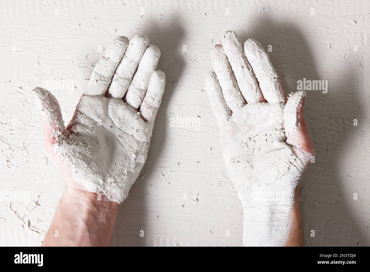 Worker hands on white plaster surface background Stock Photo - Alamy