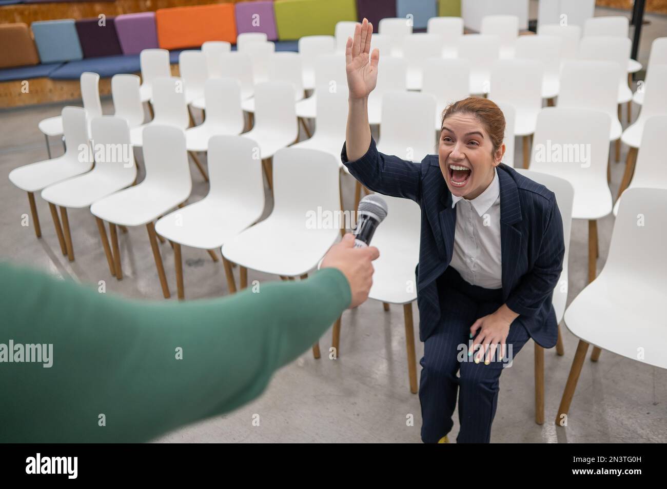 A red-haired Caucasian business woman sits in the front row in an empty ...