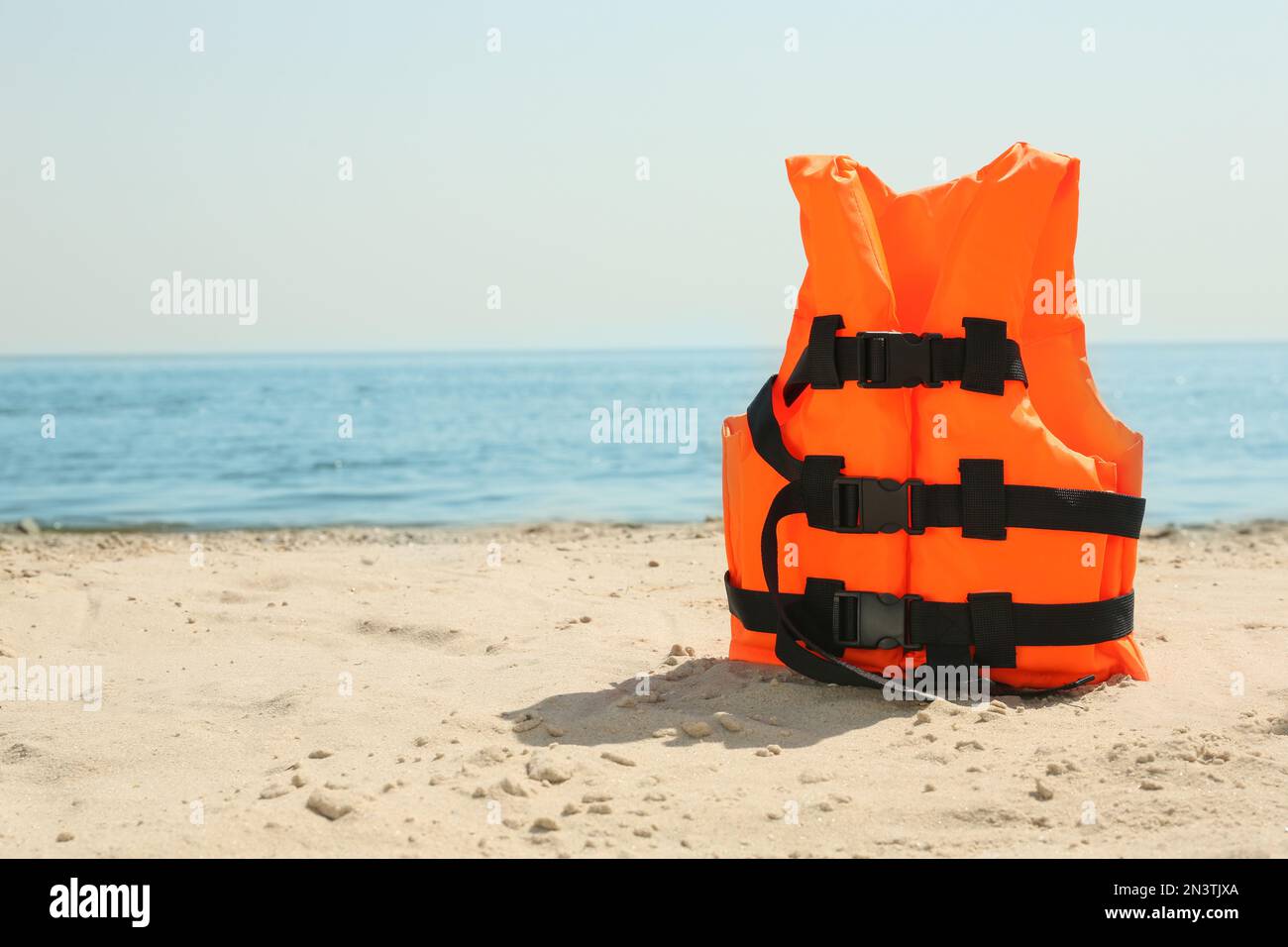 Orange life jacket on sandy beach near sea. Emergency rescue equipment ...