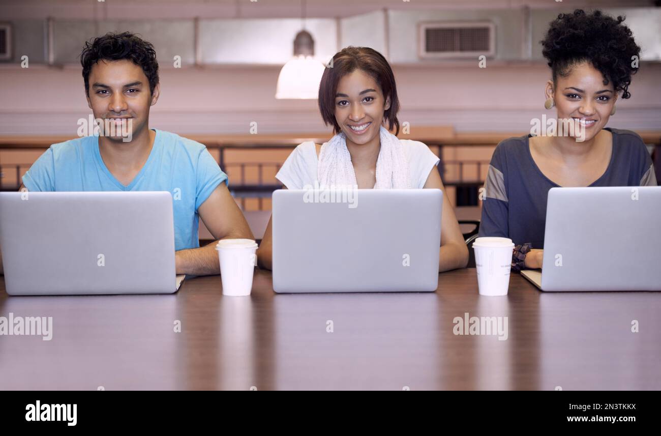 Study group dynamics. A group of students using a laptop to complete a group assignment Stock ...