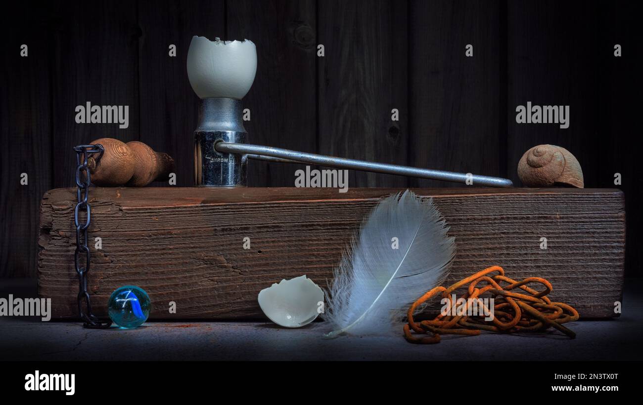 Still life with egg shells, rusty chain, feather, glass ball, wooden ...