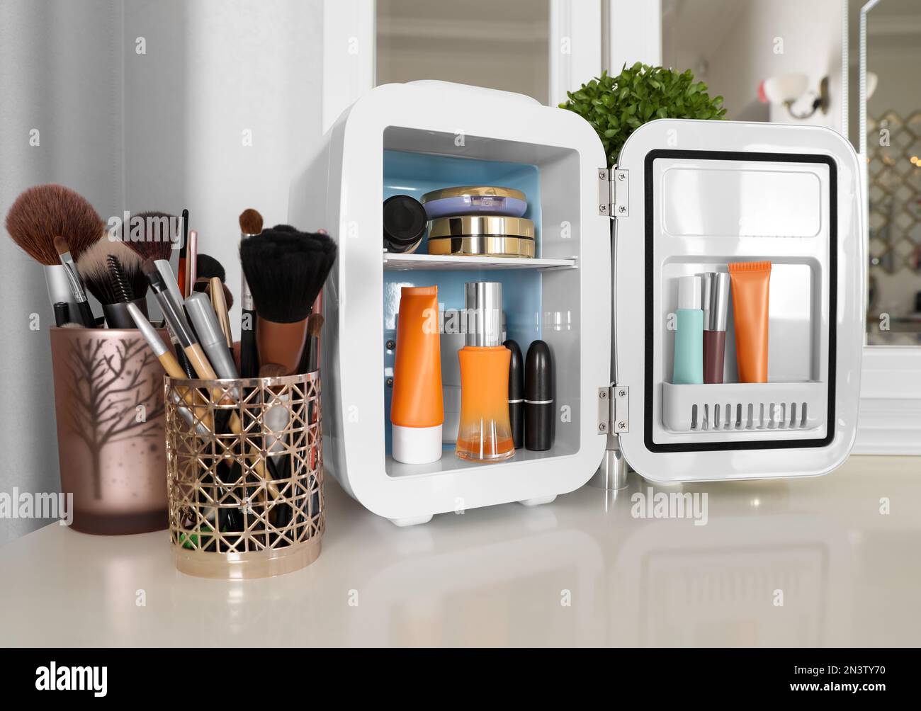 Mini fridge with cosmetic products on white vanity table Stock Photo ...