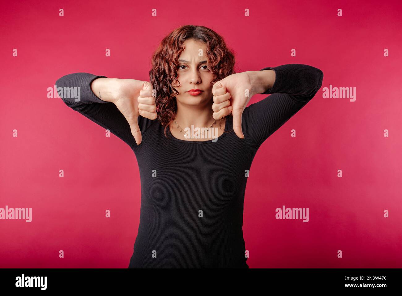 Young redhead woman wearing black ribbed dress isolated over red ...