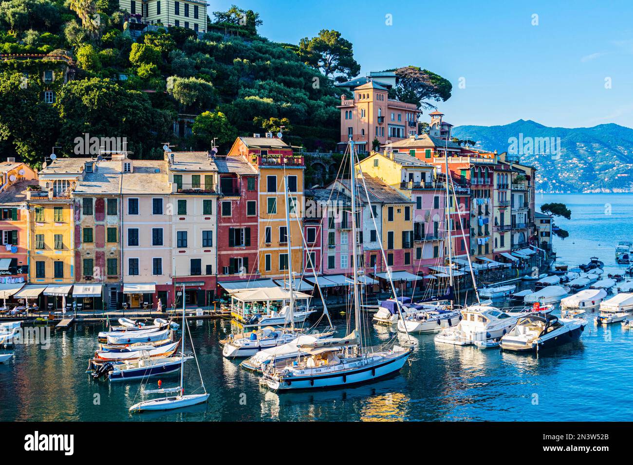 Boats anchor in the harbour of Portofino, behind them pastel-coloured ...