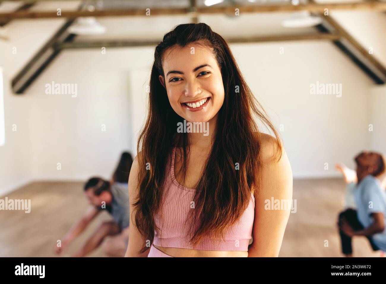 Happy female yoga instructor smiling at the camera while standing in a ...