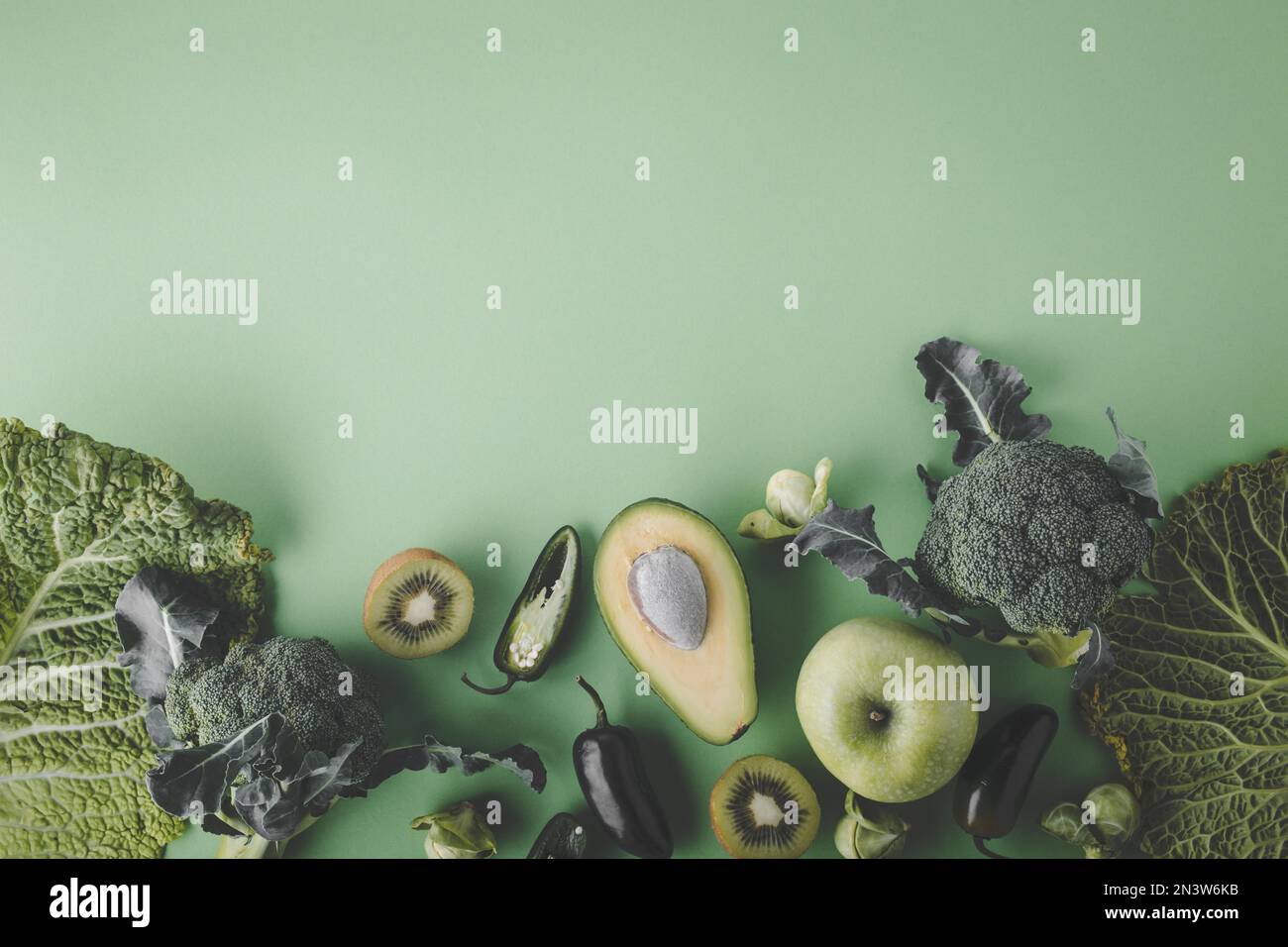 Creative layout food concept made of green fruit and vegetables on green background flat lay ...
