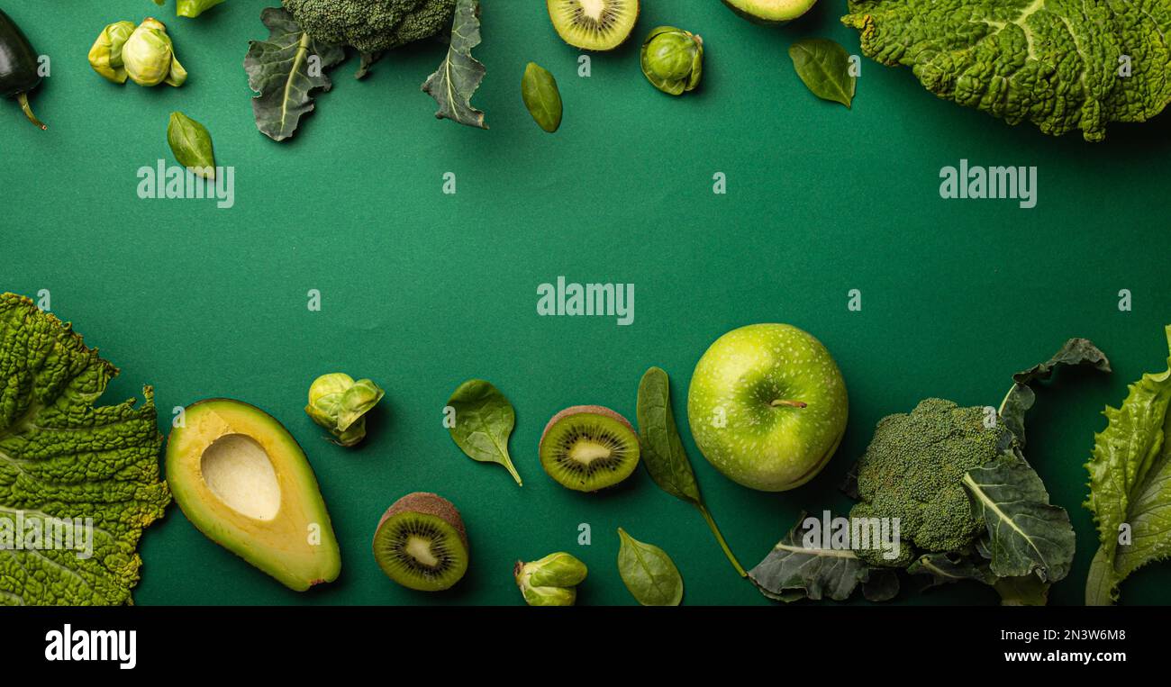 Creative layout food concept made of green fruit and vegetables on green background flat lay ...