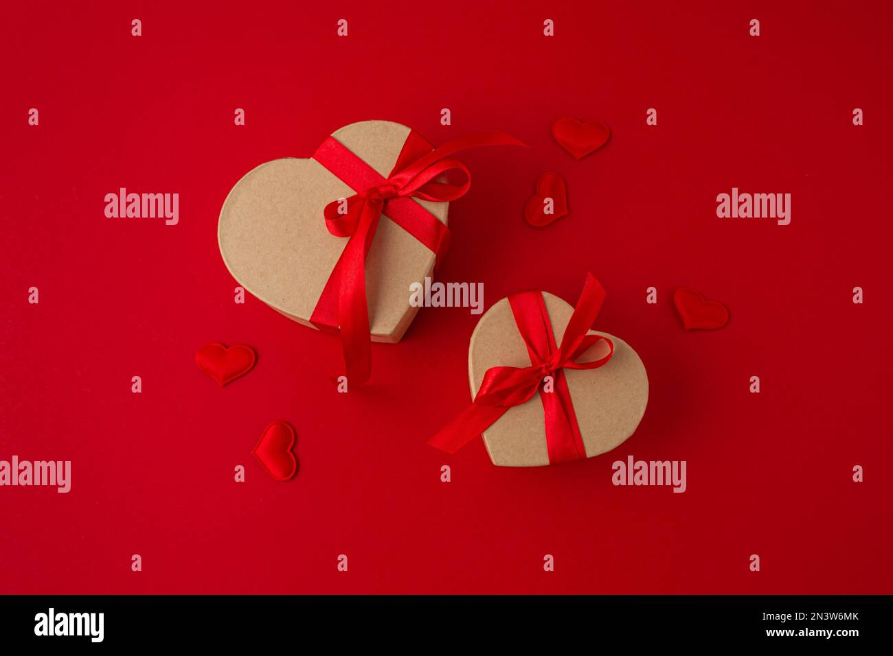 Two wrapped gift boxes in heart shape with red bow ribbon on red ...