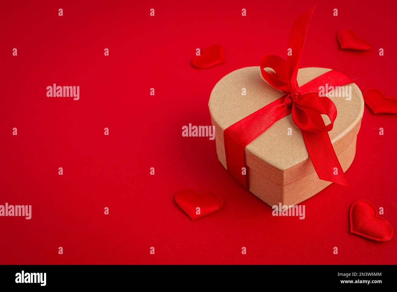 Beautiful minimal wrapped gift box heart shaped with red bow ribbon on ...