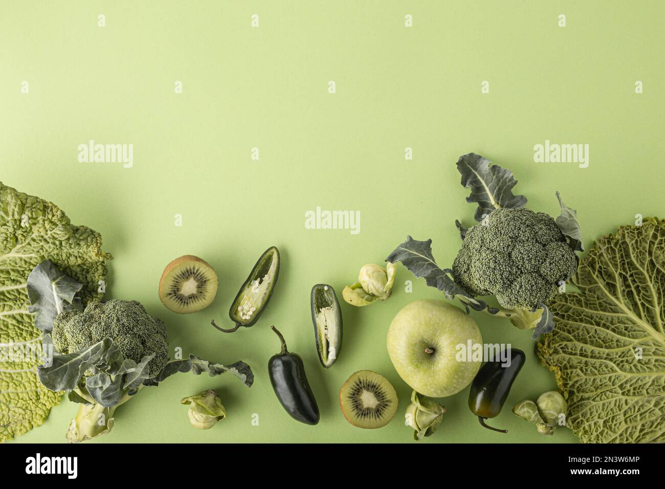 Creative layout food concept made of green fruit and vegetables on green background flat lay ...