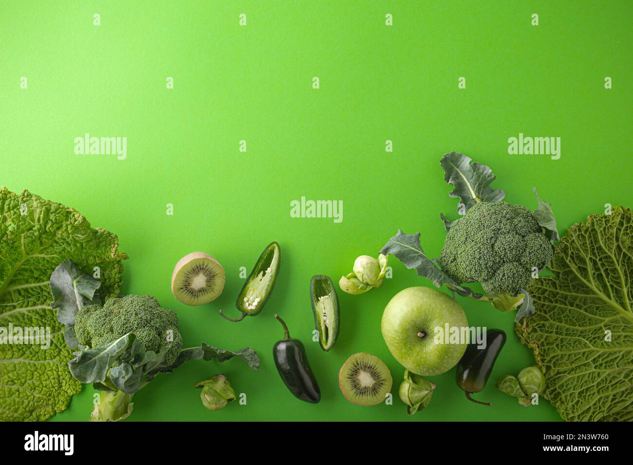 Creative layout food concept made of green fruit and vegetables on green background flat lay ...