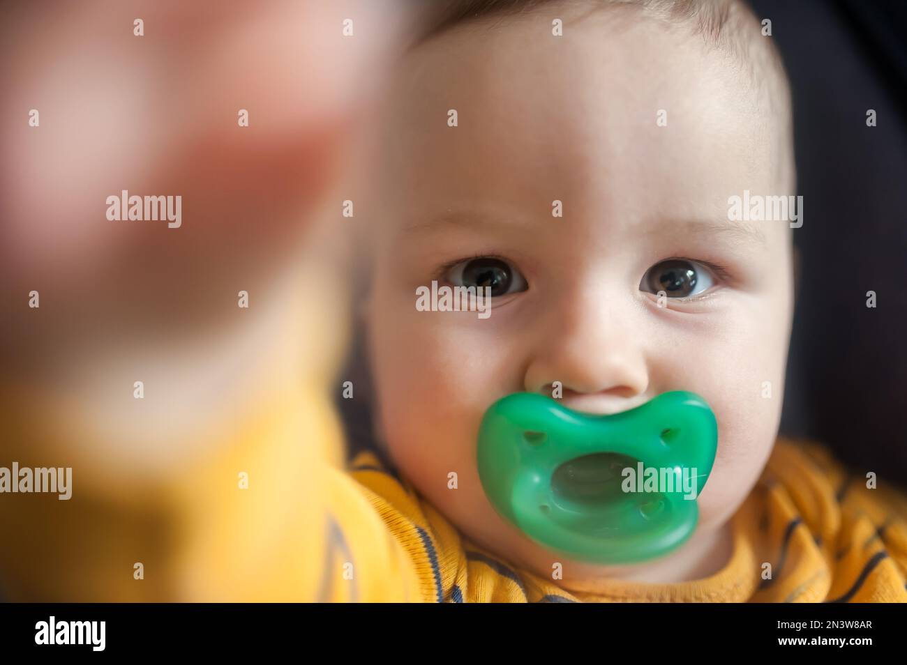 Cute baby boy stretches out his hand towards the camera in front and ...