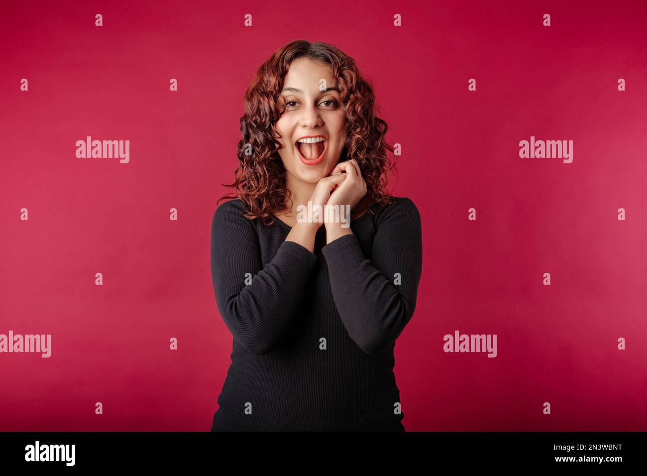 Redhead girl smiling isolated over red background looks at the camera ...