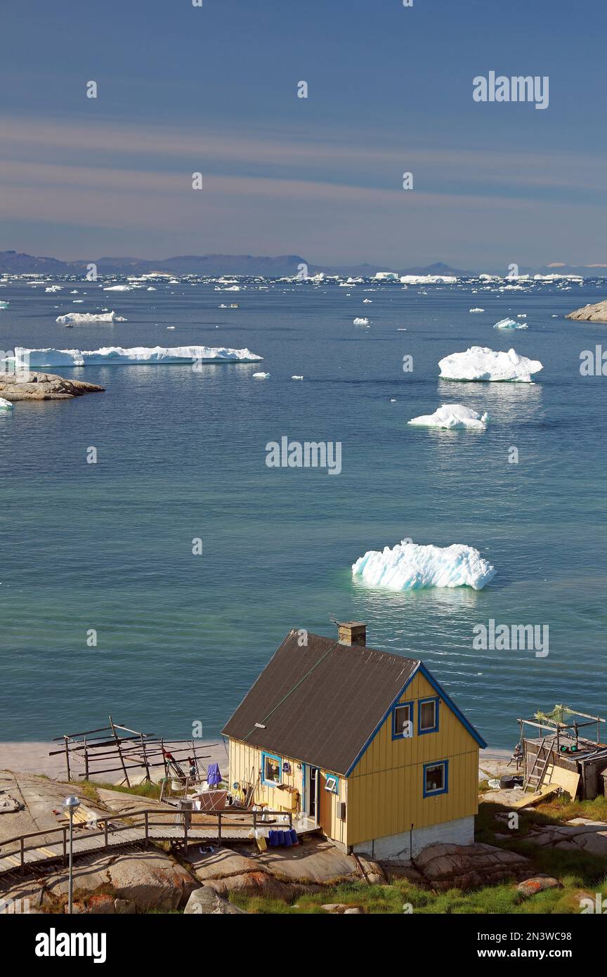 Simple dwelling house on the edge of an iceberg-covered bay, Ilulissat ...